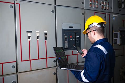 전기 엔지니어는 주 전기 제어 패널 및 스위치의 작동을 확인하고 태블릿에 값을 기록하고 전기 기술자는 공장의 전기 시스템을