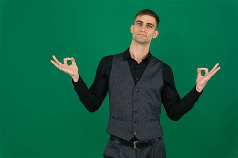 성공과 만족을 느끼는 젊은 사업가 입을 크게 벌리고 미소 짓고 녹색 배경에 손으로 괜찮은 표지판을 만듭니다 긍정적인 감정 표현에