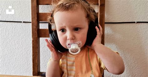 흰색 젖꼭지를 가진 아이가 테이블 근처의 갈색 의자에 앉아 헤드폰을 사용하고 있습니다 사진 Unsplash의 무료 슬픈 소년 이미지