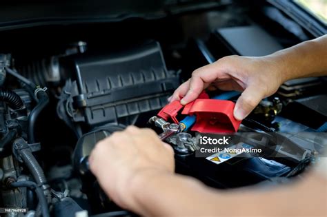 클로즈업 핸드 서비스맨은 배터리 가드를 열고 엔진룸에서 자동차 배터리 단자의 렌치 잠금 볼트를 사용하며 서비스 컨셉 및 자동차