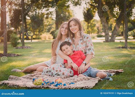 Μια ευτυχής μητέρα και τα παιδιά έχουν τη διασκέδαση στο πάρκο μια θερμή θερινή ημέρα Αυτοί Πε