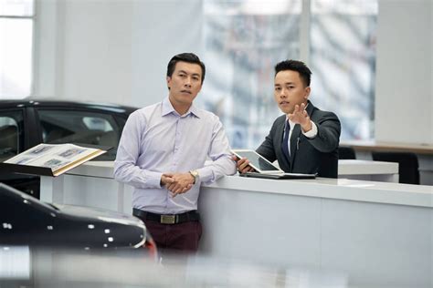 在咨询客户时年轻的亚洲汽车经销店员工在平 包图企业站