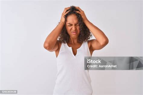 두통이 절실하고 통증과 편두통 때문에 스트레스로 고통 고립 된 흰색 배경 위에 서 캐주얼 한 티셔츠를 입고 젊은 브라질 여성 머리에 손을 T 셔츠에 대한 스톡 사진 및 기타
