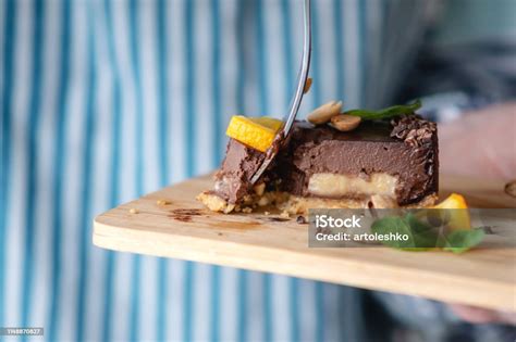 오렌지 민트 잎과 견과류와 초콜릿 케이크의 조각을 포크로 손 나누기 채식주의자를 위한 건강 한 생 디저트 개념에 대한 스톡 사진