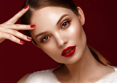 دختر زیبا با لباس سفید با آرایش کلاسیک و مانیکور قرمز عکس صورت زیبایی که در استودیو گرفته شده