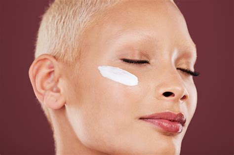 눈을 감고 얼굴 크림과 스튜디오에 있는 여성의 뷰티 스킨케어는 빨간 배경에 고립되어 있다 피부과 화장품 및 페이셜 트리트먼트용 로션 크림 또는 모이스처라이저 제품을 사용하는