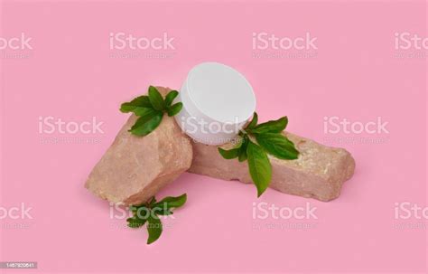 화장품의 흰색 플라스틱 항아리가 돌 연단에 서 있고 그 옆에는 분홍색 배경에 녹색 잎이 있습니다 바이오 화장품 모형 0명에 대한 스톡 사진 및 기타 이미지 Istock