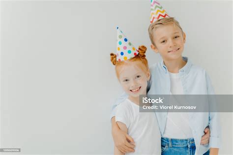 행복 한 작은 생강 주근깨 소녀와 어린 소년 포옹 하 고 기꺼이 미소 파티 모자를 착용 함께 좋은 시간을 즐길 수 흰색 배경 복사 공간 어린이 및 축제 이벤트 컨셉 2명에