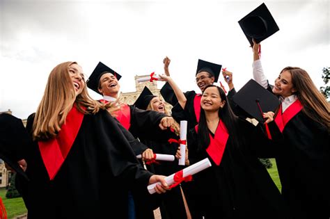 검은 망토와 절구를 입고 졸업장을 들고 야외에서 함께 축하하는 즐거운 젊은 졸업생들 16 17 살에 대한 스톡 사진 및 기타 이미지 16 17 살 18 19세 20