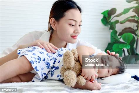 귀여운 유아 아기 소녀는 침대에서 테디베어 장난감을 껴안고 자고 젊은 아름다운 엄마는 졸린 딸 아이를 보고 엄마는 잠자는 아이를 위로하고 부모는 집에서 아이를 돌보고 가족을