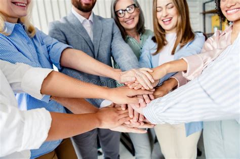 Group Of Professionals Joining Hands In A Collaborative Office Setting