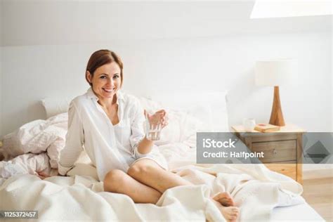 젊은 여 자가 밤 축구 실내에 앉아 침대에서 아침에로 물 들고 여자에 대한 스톡 사진 및 기타 이미지 여자 침대 한 명의 여자만 Istock