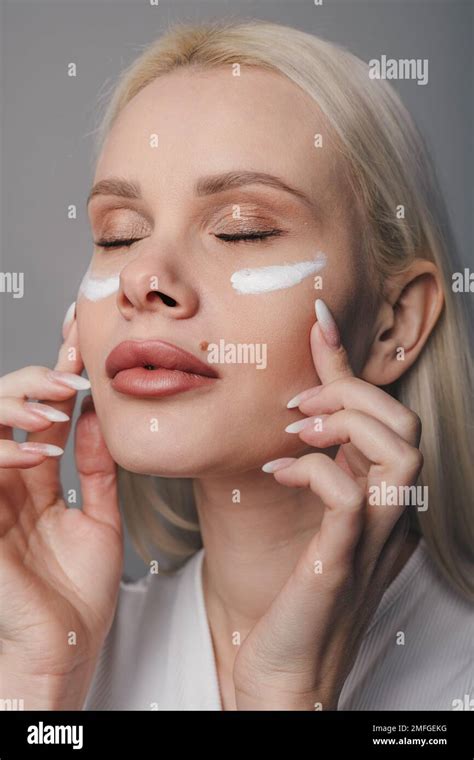 Beautiful Young Woman With Natural Makeup Applying Cream On Her Fresh