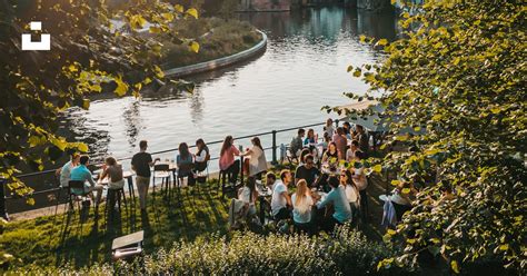 한 무리의 사람들이 강 옆 벤치에 앉아 있다 사진 Unsplash의 무료 태양 이미지