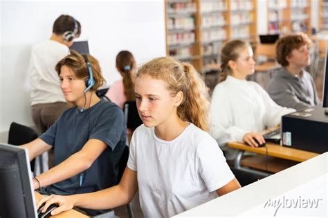 Pupils Using Computers At Lesson Teacher Teaching Them In Classroom Posters For The Wall