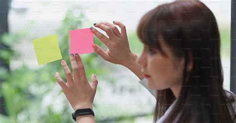 유리 벽에 화려한 스티커 메모를 넣는 여성 직원의 클로즈업 사진 Unsplash의 그것의 게시 이미지