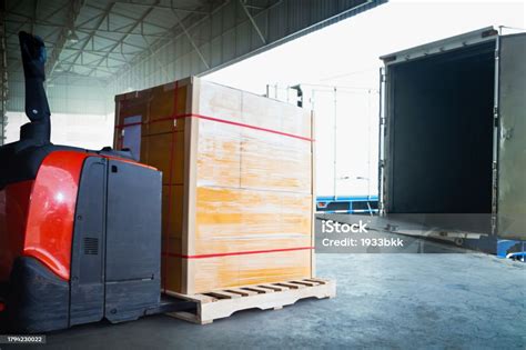 전기 지게차 팔레트 잭 및 패키지 상자는 팔레트에 플라스틱을 감쌌습니다 도크 창고에서 적재하는 트럭 유통 창고 배송 소모품 배송 화물 트럭 물류 0명에 대한 스톡 사진 및