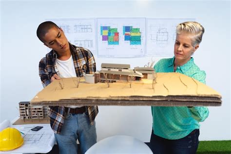 Premium Photo Male And Female Architects Looking At Model Structure Of House