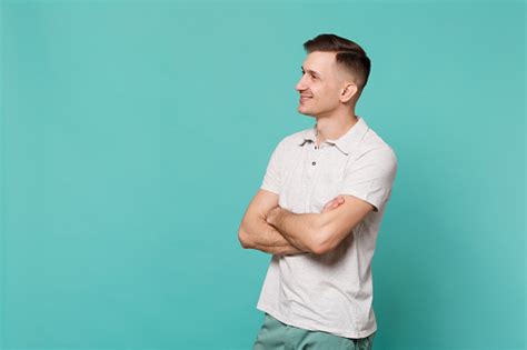 캐주얼 옷에 젊은 남자의 초상화를 옆으로 찾고 스튜디오에서 파란색 청록색 벽 배경에 고립 접힌 손을 잡고 사람들은 진심으로 감정 라이프 스타일 개념입니다 복사 공간을 모의