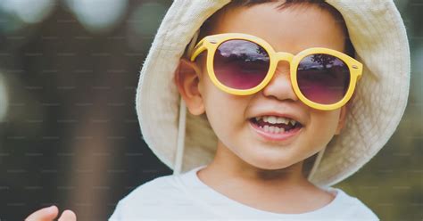 모자와 노란 선글라스를 쓰고 야외에서 카메라를 바라보는 행복한 아시아 소년의 초상화 사진 Unsplash의 아이 이미지