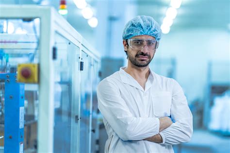 보호 장비를 착용한 자신감 넘치는 식품 가공 감독자가 공장에서 기계 옆에 팔짱을 끼고 서 있는 모습은 리더십 품질 보증 및 운영 안전을 상징합니다 고기에 대한 스톡 사진 및