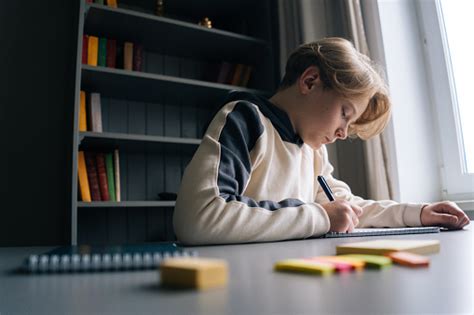 어두운 방에 책상에 앉아 펜과 카피 북에 메모를 만드는 초점을 맞춘 학생 소년의 초상화 교육에 대한 스톡 사진 및 기타 이미지 교육 수필 쓰기 Istock