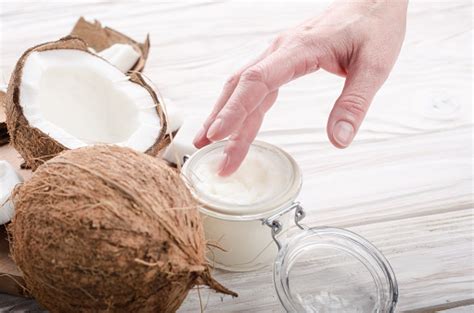 인간의 손바닥에 코코넛 오일과 밀폐 유리 항아리에 껍질 조각이 옆에 흰색 나무 테이블 가꿔주기에 대한 스톡 사진 및 기타 이미지