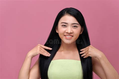 Portrait Of Smiling Asian Woman Posing And Touching Dark Long Hair