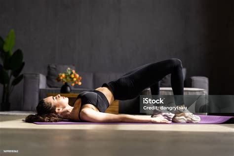 체조를 하는 젊은 여성의 측면 모습 피트니스 스튜디오나 집에서 하프 브릿지 포즈 가냘픈에 대한 스톡 사진 및 기타 이미지