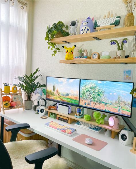 Two Computer Monitors Sitting On Top Of A Desk In Front Of A Plant And Other Items