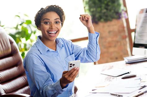 스마트 폰을 사용하고 흥분으로 미소 지으며 사무실에서 성공을 축하하는 행복한 젊은 아프리카 계 미국인 사업가 25 29세에 대한 스톡 사진 및 기타 이미지 Istock
