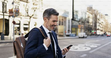 양복을 입은 성숙한 남성 기업가의 측면 모습과 배낭 횡단 도로와 휴대 전화에서 메시지를 읽고 사진 Unsplash의 양복 이미지