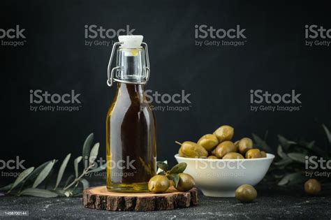 올리브 오일이 든 병 옆에 흰색 그릇에 담긴 녹색 올리브와 검은색 배경에 나뭇잎 냉간 압착 오일 한 병 전통적인 그리스와 이탈리아 음식 병에 대한 스톡 사진 및 기타 이미지