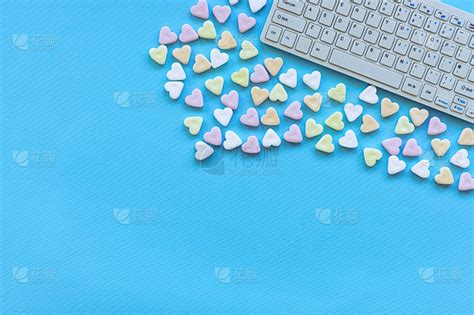 心形糖果和键盘电脑在蓝色的桌子上情人节的概念俯视图平放复制空间