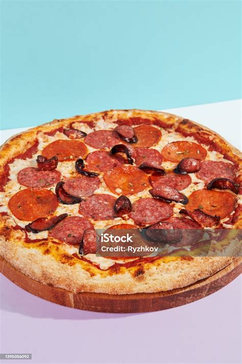 소시지 살라미 페퍼로니를 색칠한 배경에 곁들인 이탈리아 피자 살라미와 페퍼로니를 곁들인 고기 피자는 파란색으로 최소한의 스타일로 제공됩니다 색상 배경을 가진 미국 피자 배달