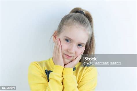 흰색 배경에 노란색 스웨터 또는 티셔츠를 입은 재미있고 시원하고 예쁘고 멋진 소녀가있는 생생하거나 다채로운 작품은 실망스럽거나 후회하는 포즈로 쉽게 추출할 수 있으며 뺨에