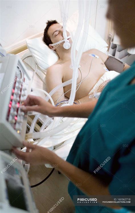 Nurse Adjusting Controls On Ventilator Attached To Unconscious Patient Technological Tubes