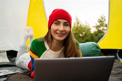 빨간 모자를 쓴 웃는 프리랜서 여자가 관광 텐트 안에서 노트북으로 작업하고 있다 30 34세에 대한 스톡 사진 및 기타 이미지 30 34세 가상현실 관광 Istock