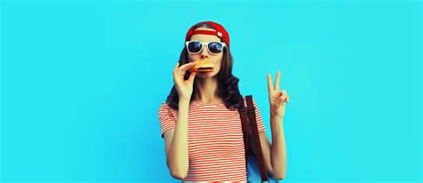 파란색 배경에 야구 모자를 쓰고 햄버거 패스트푸드를 가진 행복한 젊은 여성의 초상화 인물 사진에 대한 스톡 사진 및 기타 이미지 인물 사진 20 29세 25 29세