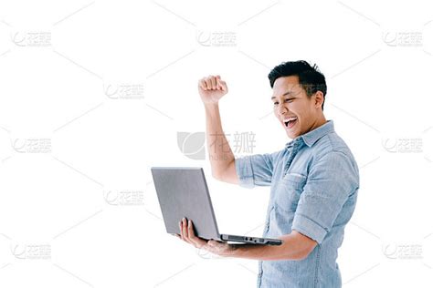 亚洲人拿着笔记本电脑，举起手臂庆祝成功