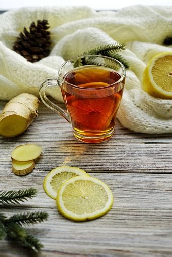 레몬과 생강 뿌리와 차 유리 컵 조각 민트 잎 여자의 모직 장갑 및 니트 스카프 야외의 바탕에 시골풍 나무 테이블에 유리 접시에