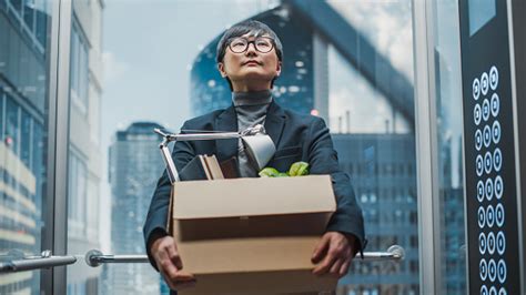 현대 비즈니스 센터의 유리 엘리베이터를 타고 사무실에 첫날 에 오는 신입 사원 오피스 액세서리 랩 및 책상 용 공장과 골판지 상자를 들고 행복한 일본 관리자 건축에 대한