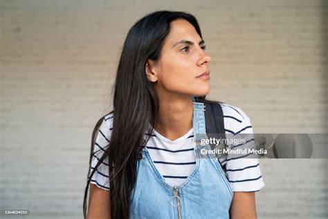 Smiling Latin Mid Adult Woman Standing Against White Brick Wall High