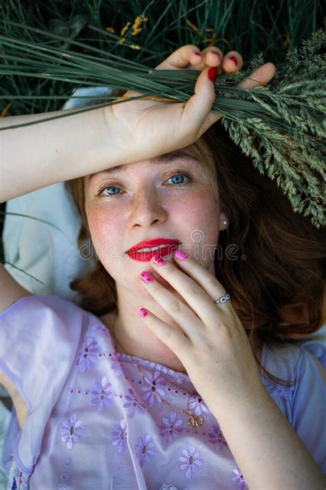 Close Up Red Head Woman With Red Lips Lying In The Grass Stock Image