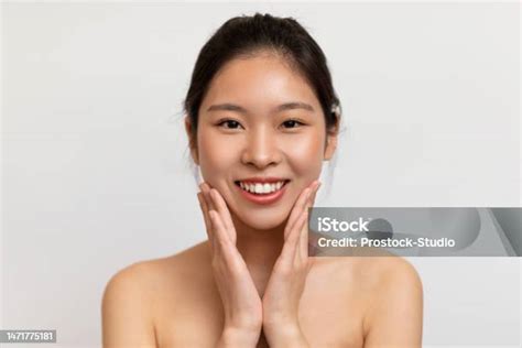 그녀의 뺨을 만지고 카메라에 미소 짓는 행복한 젊은 아시아 여성 스킨케어 치료를 즐기는 한국 여성 18 19세에 대한 스톡 사진 및 기타 이미지 Istock