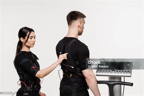 남자와 여자는 흰색 배경에 근육을 자극하기 위해 전기 충격을 사용하는 Ems 슈트의 접촉기를 연결합니다 전기 근육 자극 슈트를 입은 스포츠 그룹 훈련 18 19세에 대한