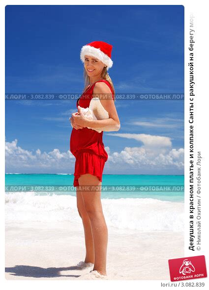 Девушка в красном платье и колпаке Санты с ракушкой на берегу моря Стоковое фото № 3082839