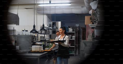 행복한 요리사와 요리사가 레스토랑 주방에서 요리를 하고 원형 문 창문을 통해 총을 쐈습니다 사진 Unsplash의 실내 이미지