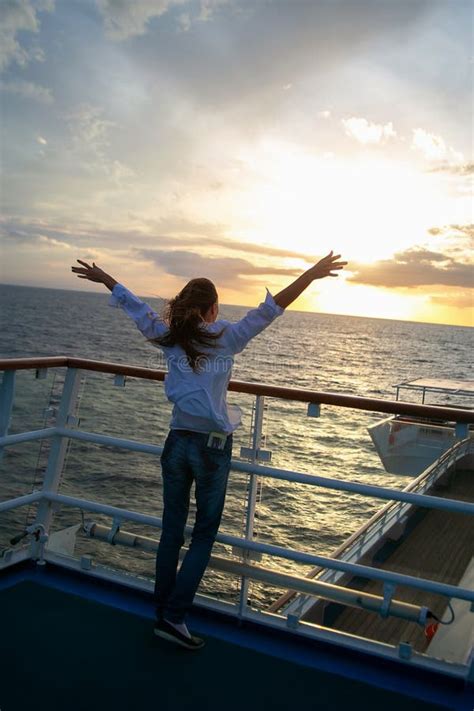 Young Woman Standing On Board Ship With Arms Outstretched Towards Wind
