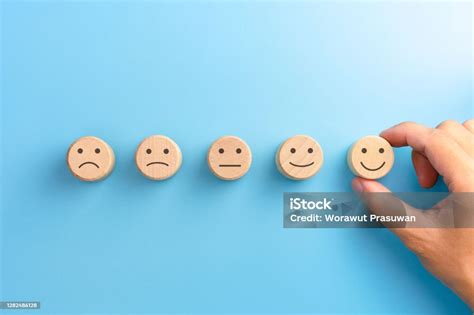 고객 서비스 평가 및 만족도 설문조사 개념 클라이언트의 손은 파란색 배경에 나무 큐브에 행복한 얼굴 미소 얼굴 아이콘을 골랐다 복사 공간 직원에 대한 스톡 사진 및 기타